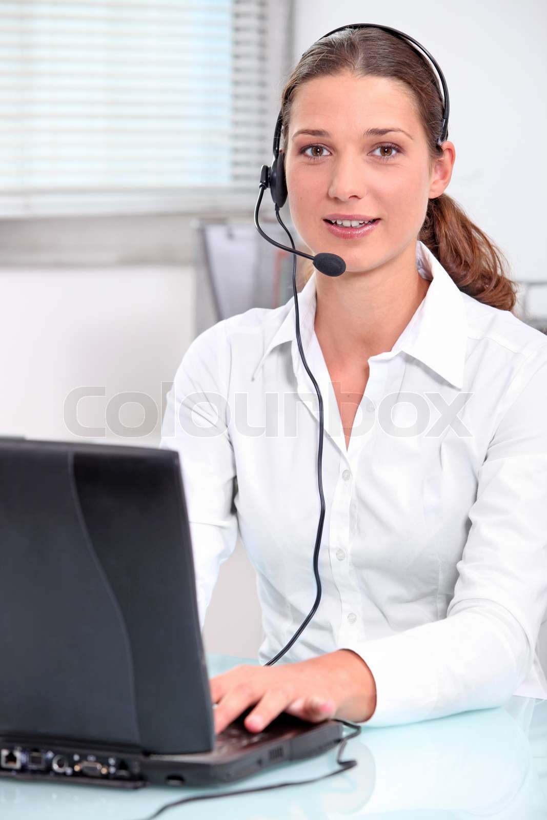Young secretary with headphones and microphone | Stock image | Colourbox
