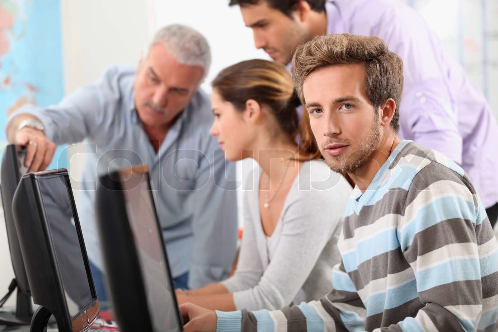 Teacher and students gathered around computer screen | Stock image ...