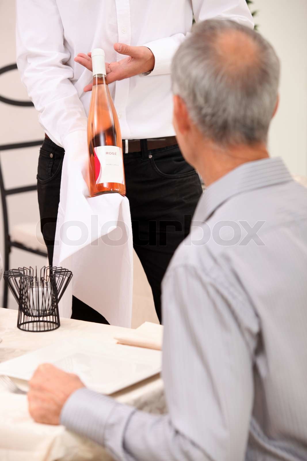 Waiter showing bottle of wine to man dining alone | Stock image | Colourbox