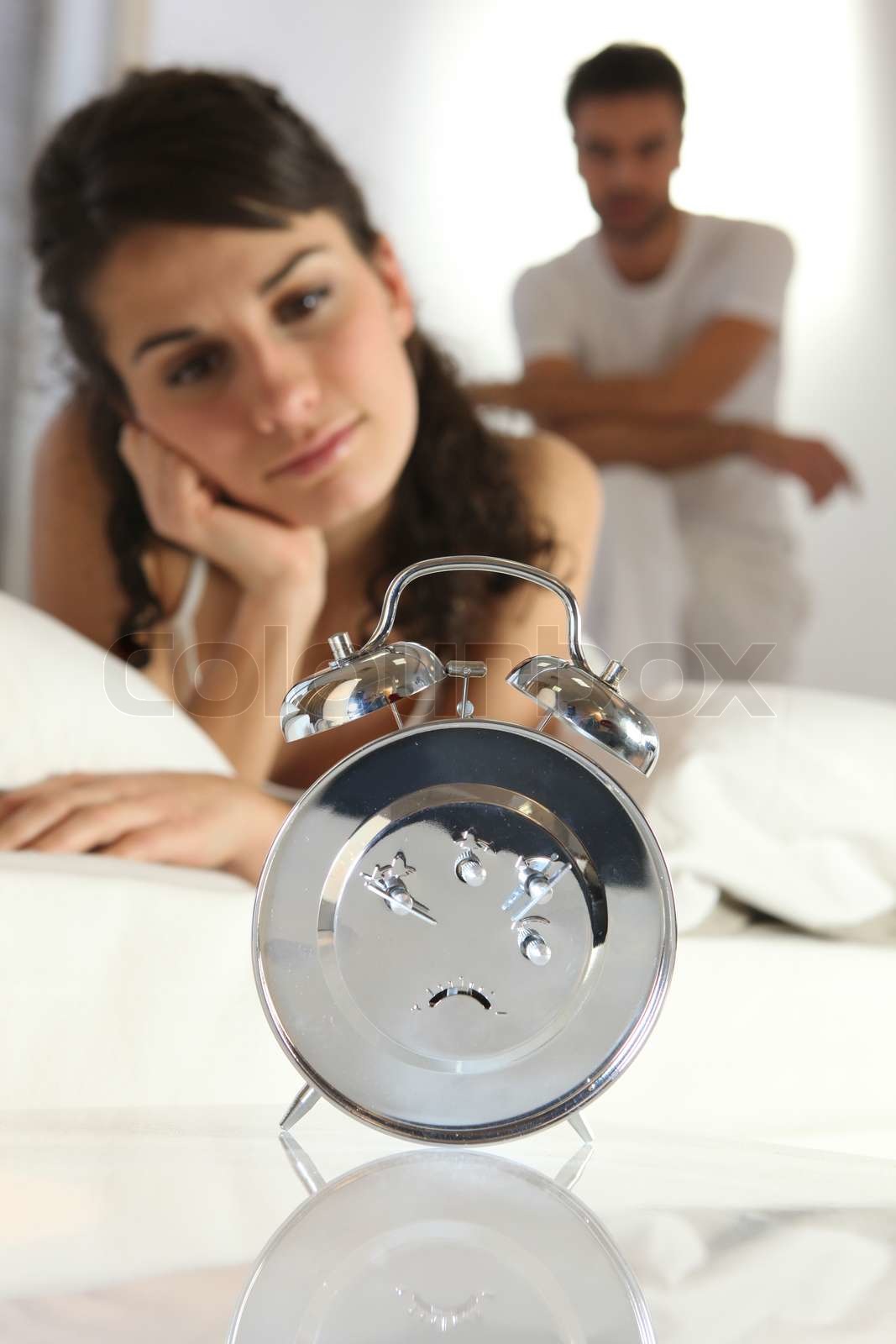 Couple staring at an alarm clock | Stock image | Colourbox