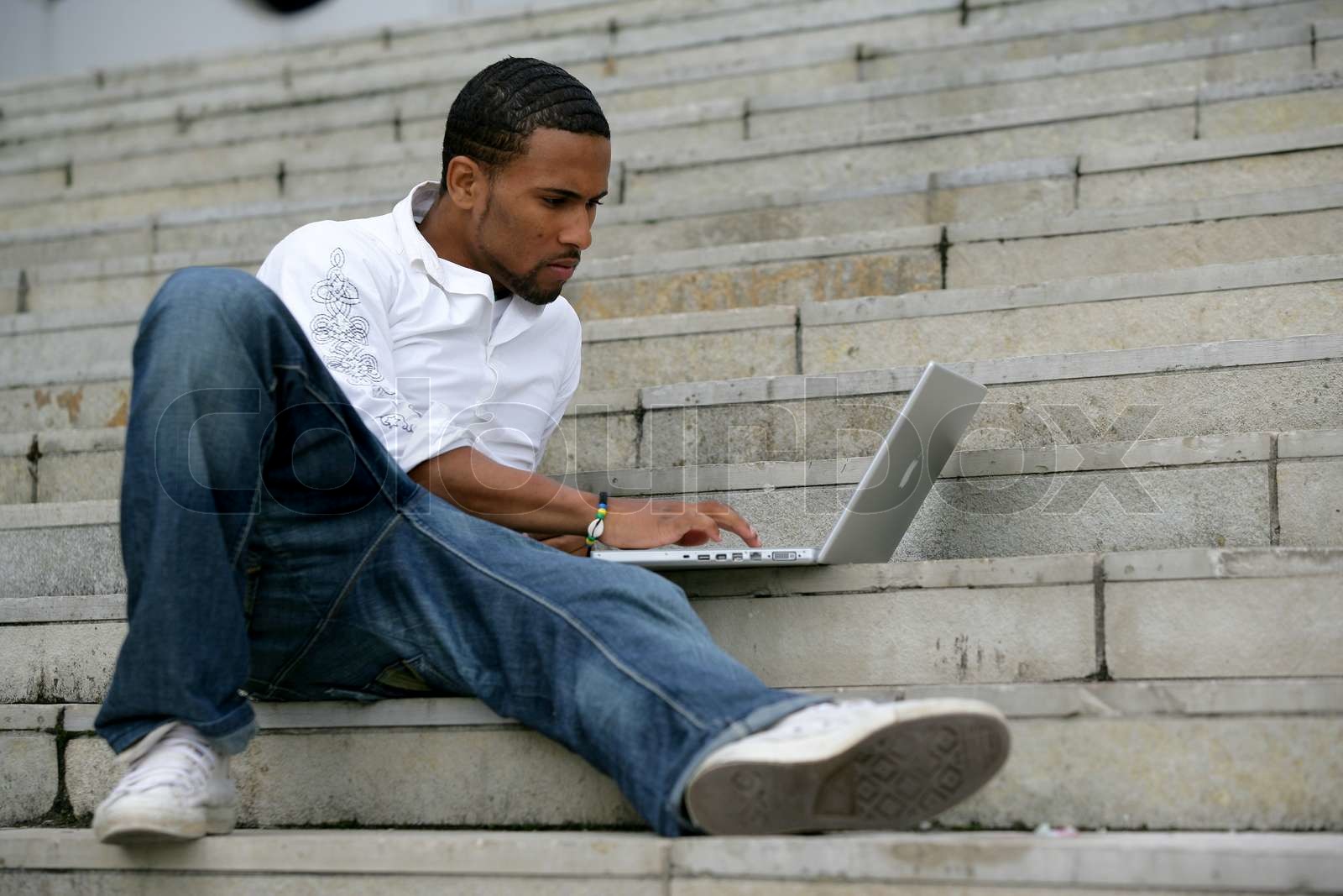 sort mand, der arbejder på laptop i trapper | Stock foto | Colourbox