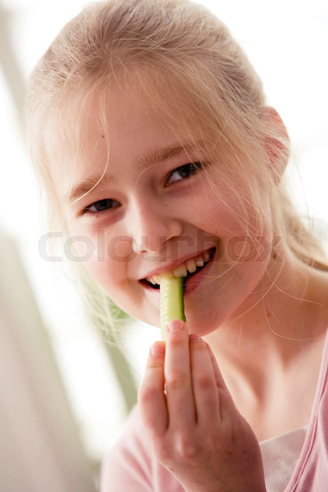 A caucasian girl eating fresh cucumber | Stock image | Colourbox