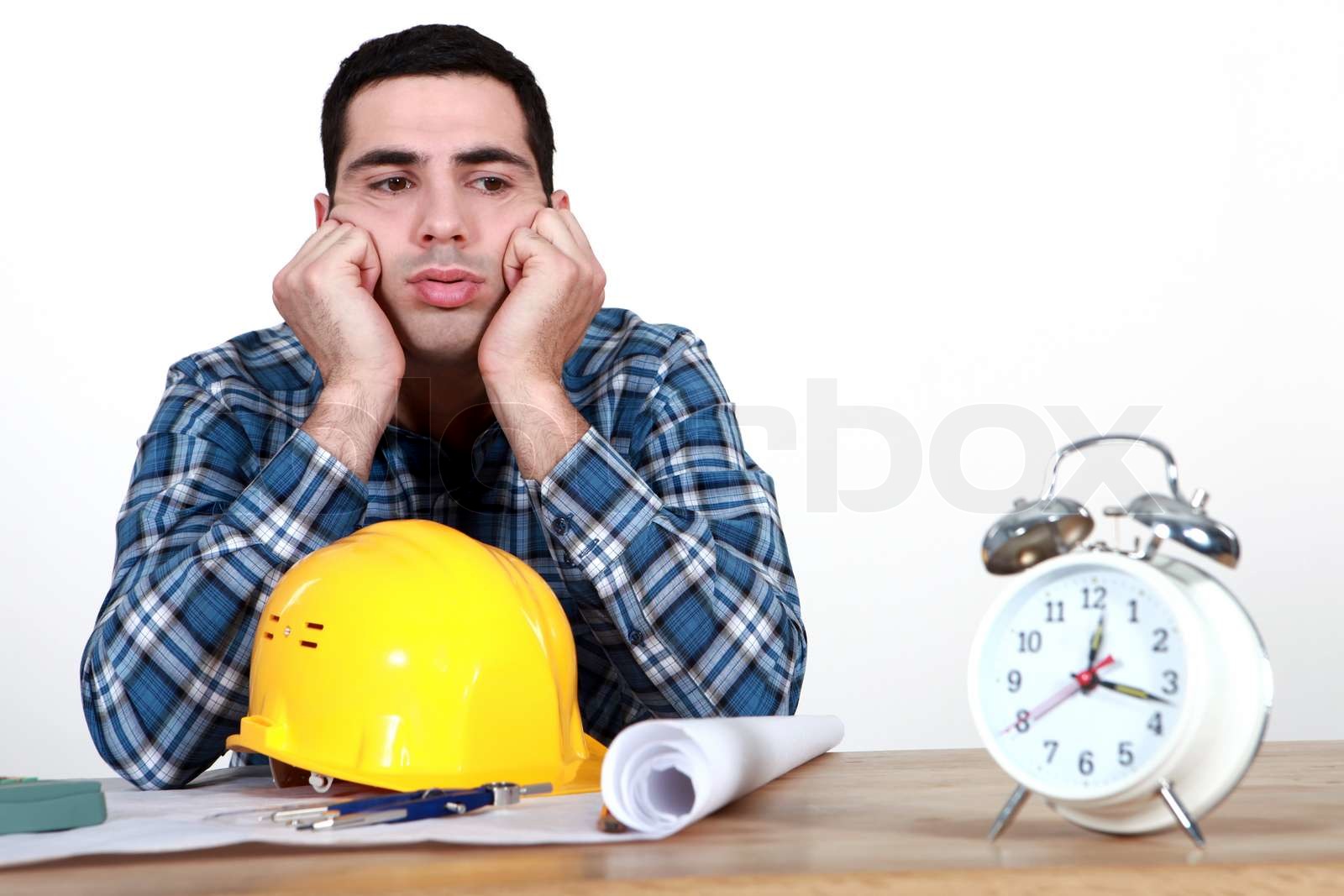Construction worker with plans and an alarm clock | Stock image | Colourbox