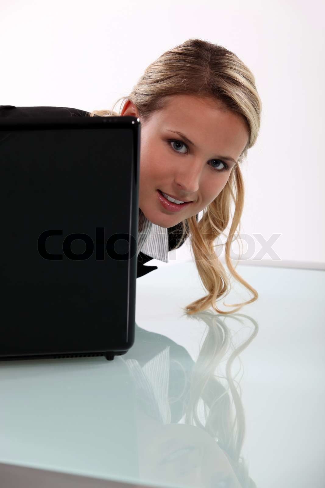 Woman peering around her laptop | Stock image | Colourbox