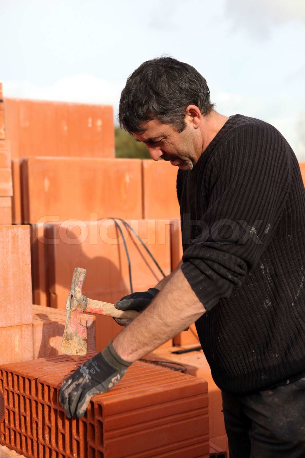 Builder shaping a brick | Stock image | Colourbox