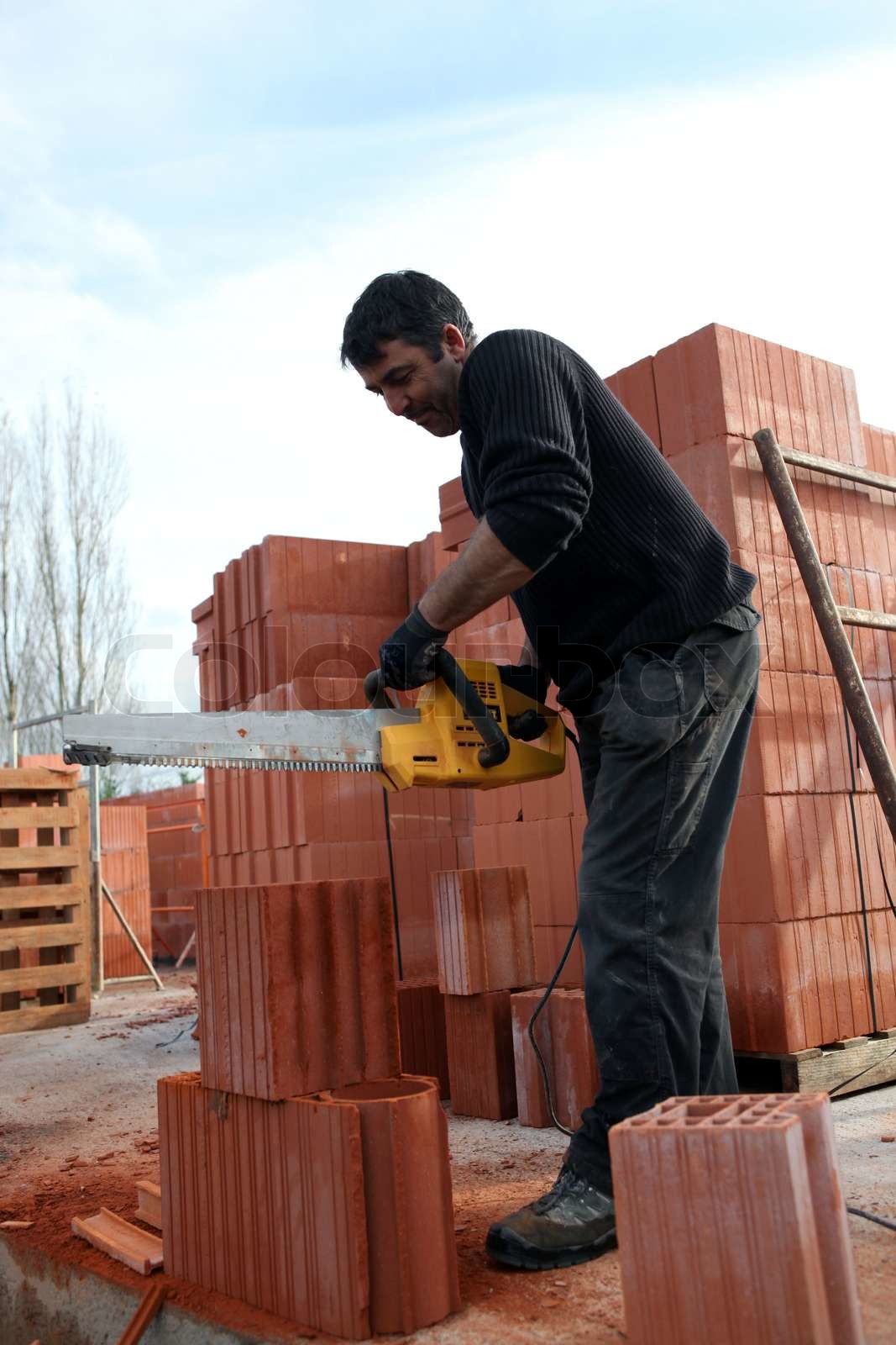 Man sawing through bricks | Stock image | Colourbox