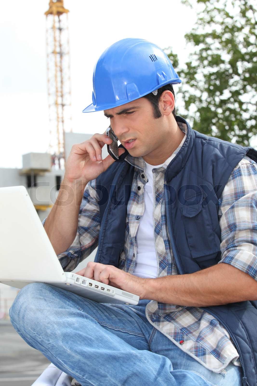 Construction worker with computer and phone | Stock image | Colourbox