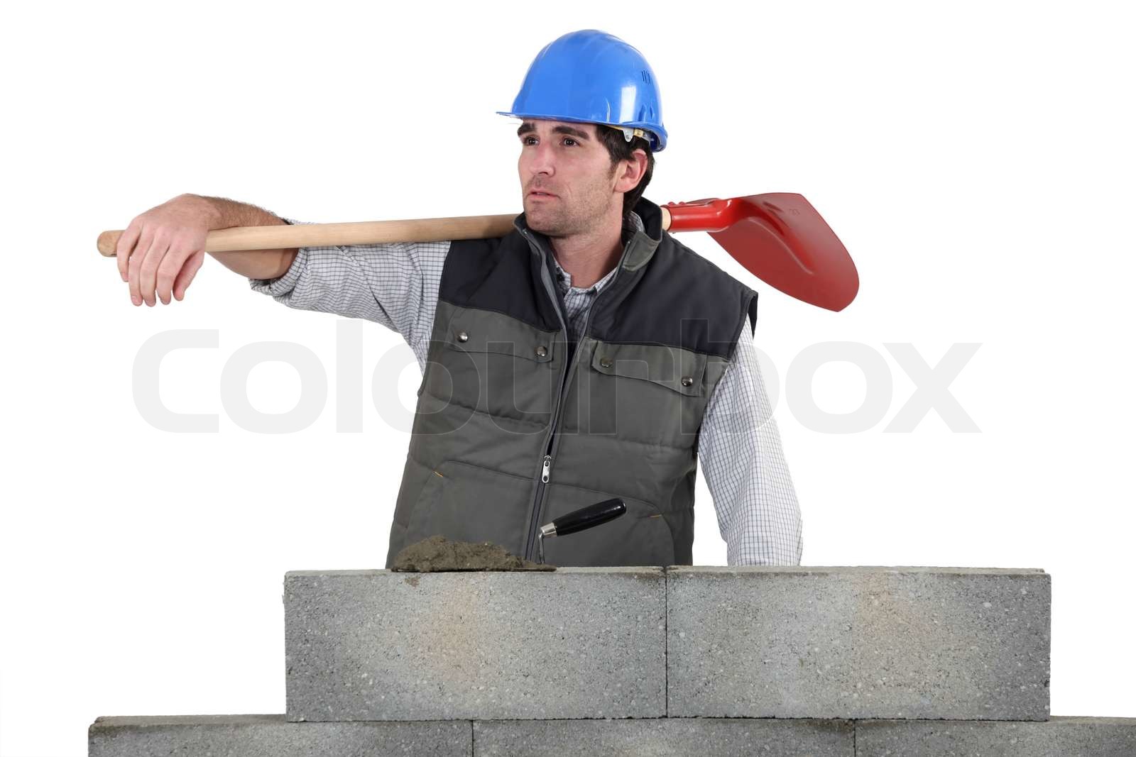 Man with spade stood by unfinished wall | Stock image | Colourbox