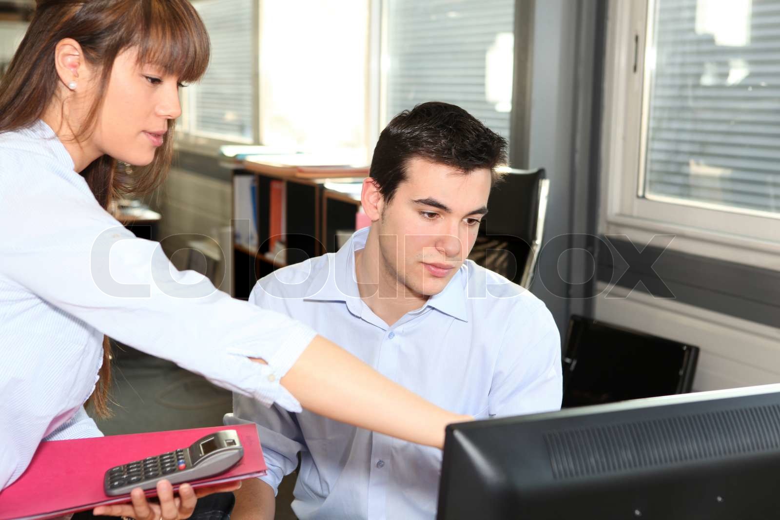 Woman explaining something on a computer to her colleague | Stock image ...