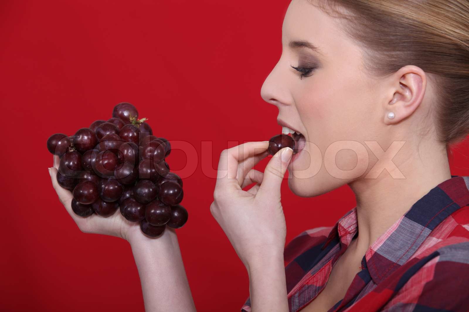 Woman eating red grapes | Stock image | Colourbox