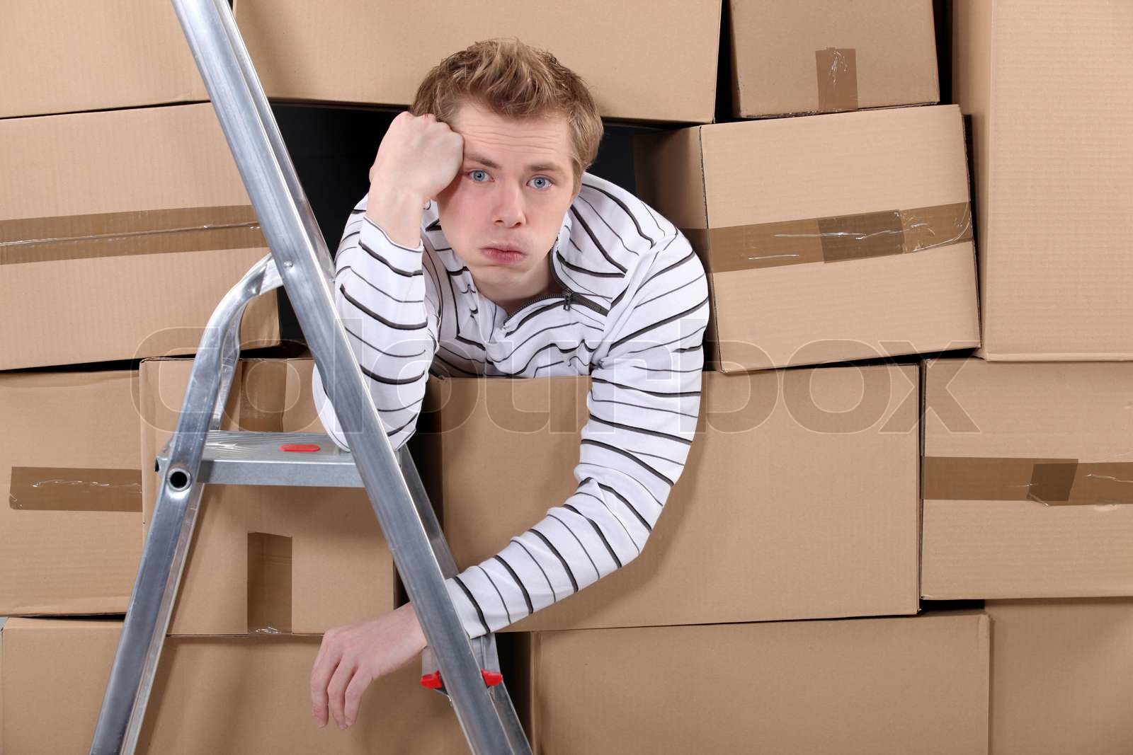 Man stuck behind stacks of cardboard boxes | Stock image | Colourbox