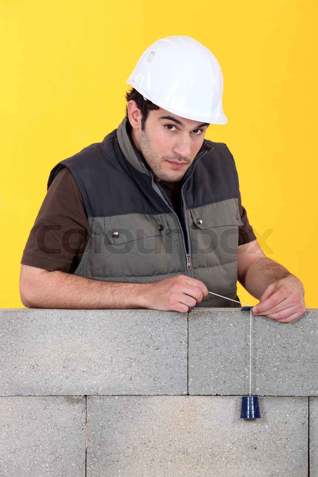 Bricklayer with a plumb line | Stock image | Colourbox