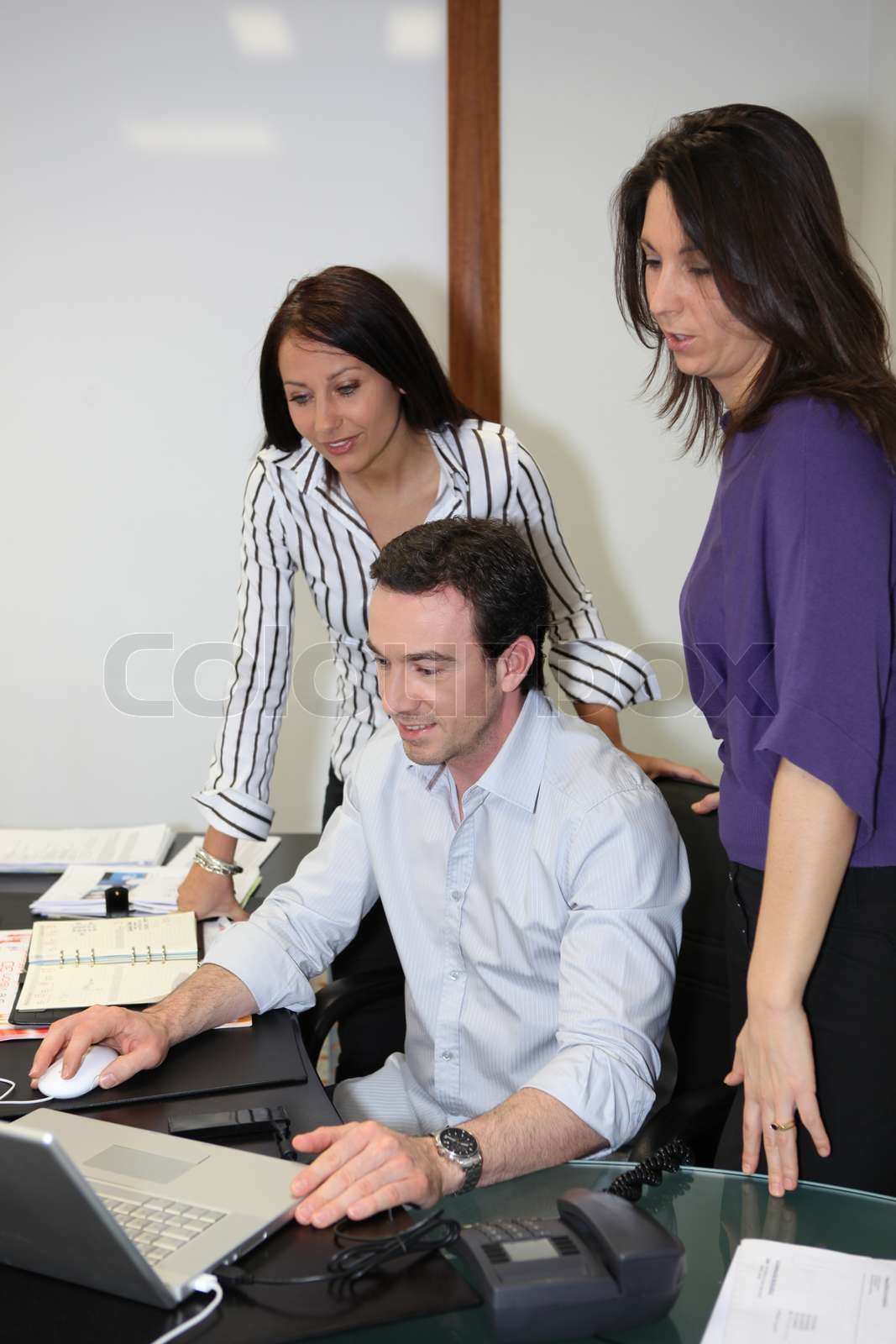 People working around a computer | Stock image | Colourbox