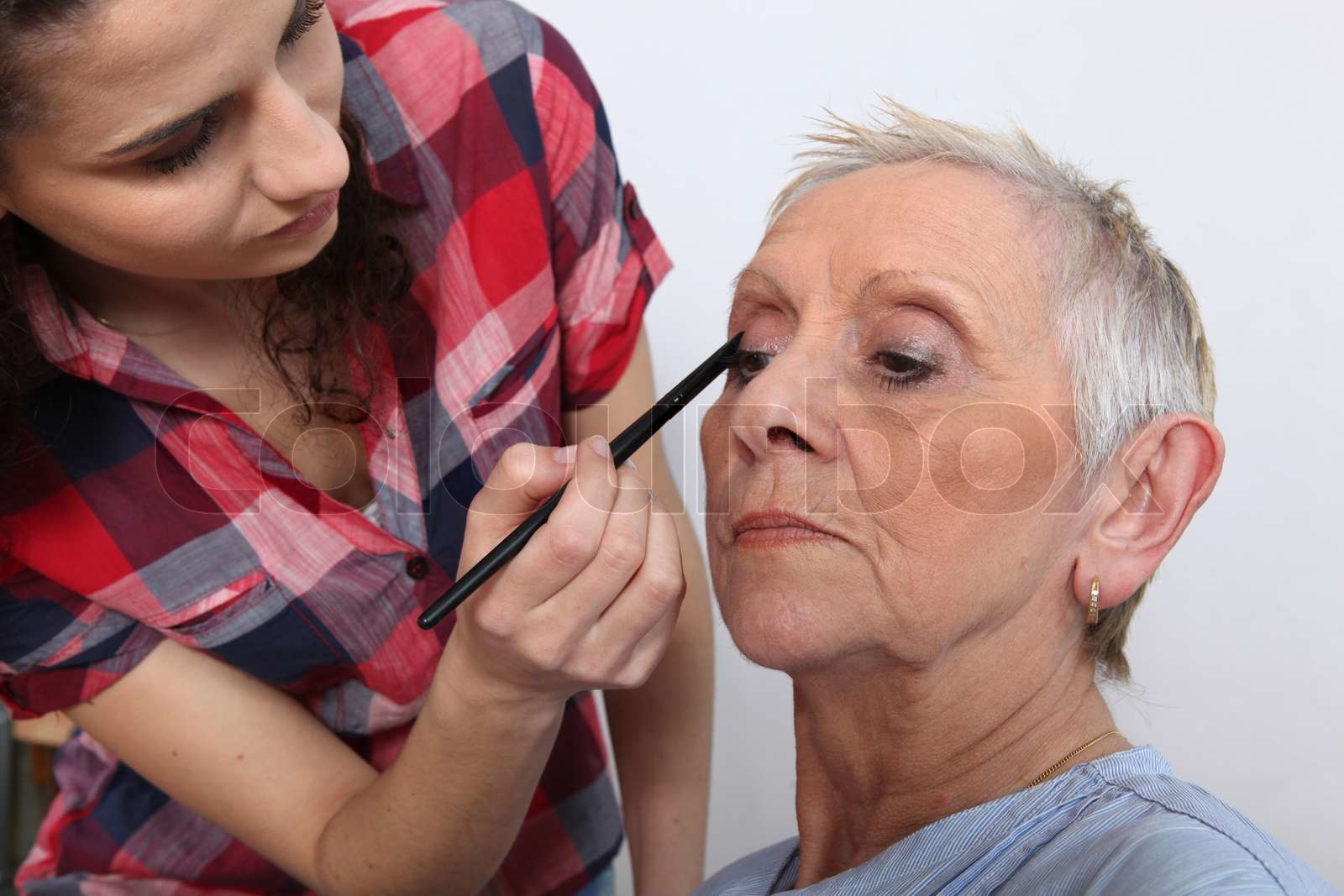 Woman applying makeup to an older lady | Stock image | Colourbox
