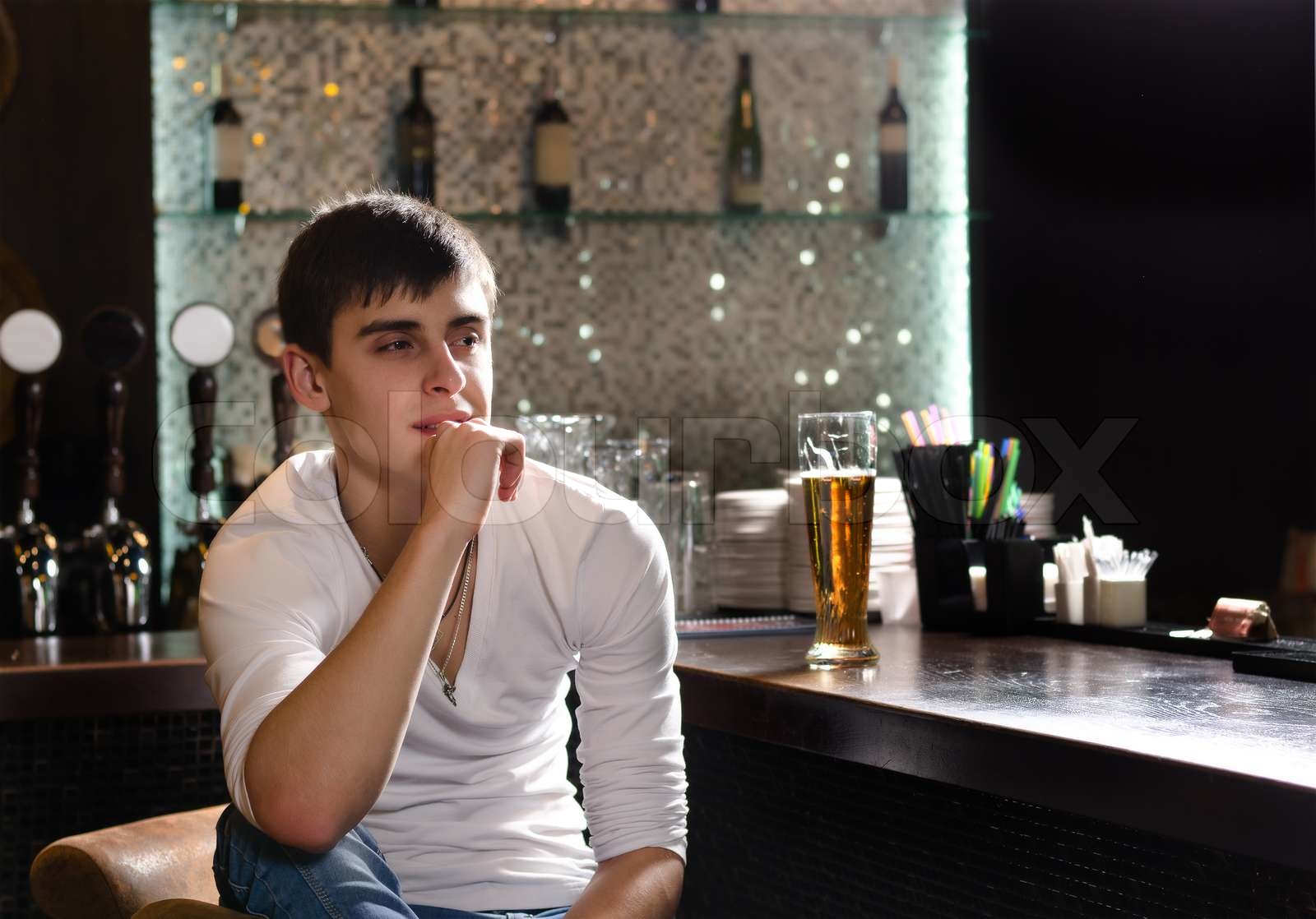 Thoughtful young man sitting thinking in a bar | Stock image | Colourbox