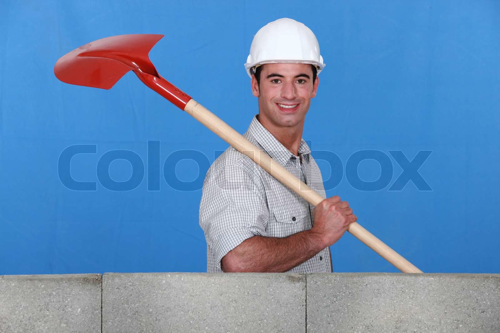 Mason with shovel building wall | Stock image | Colourbox