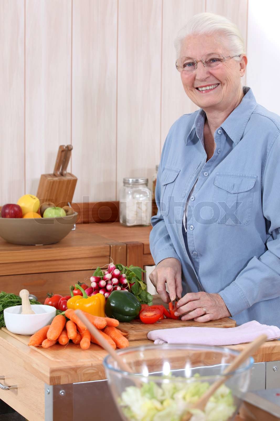 Old lady chopping vegetables | Stock image | Colourbox