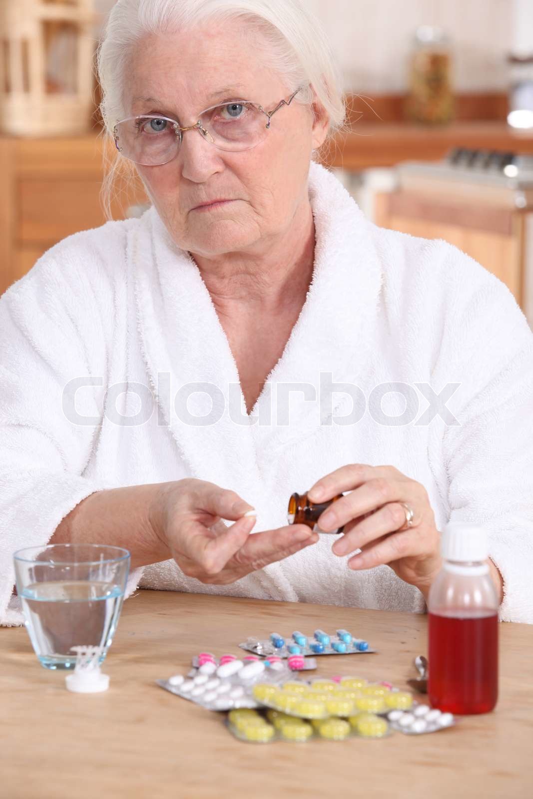Unhappy elderly lady taking her medication | Stock image | Colourbox