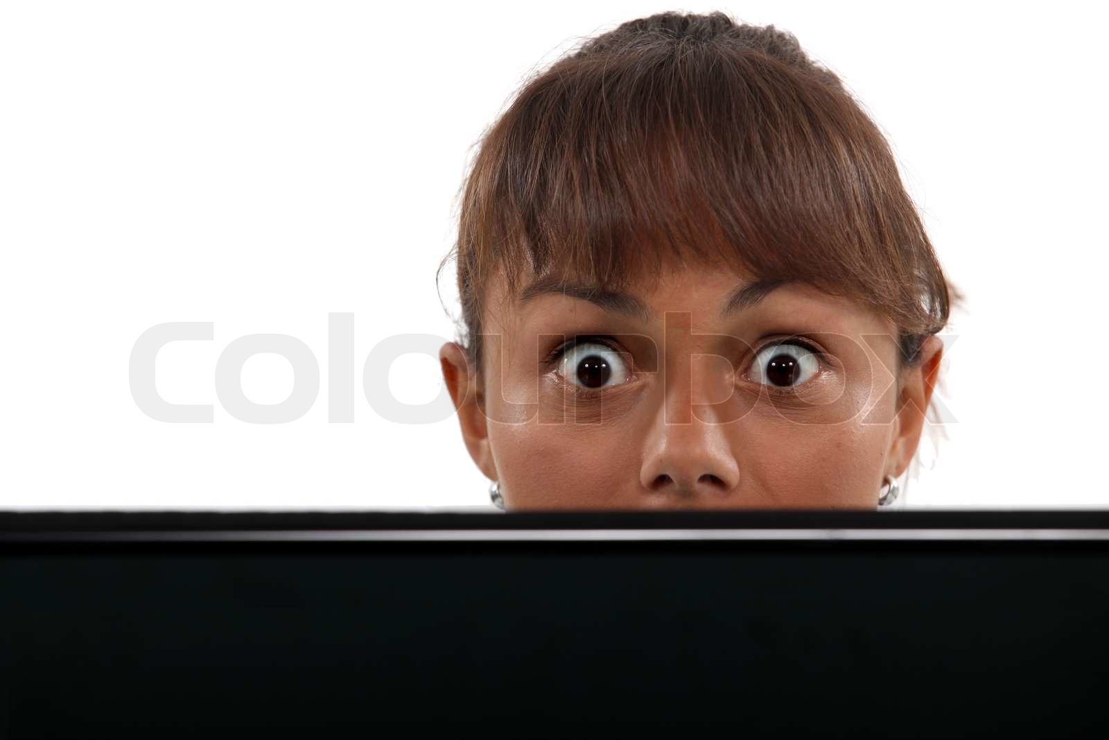 Woman peering over her laptop | Stock image | Colourbox