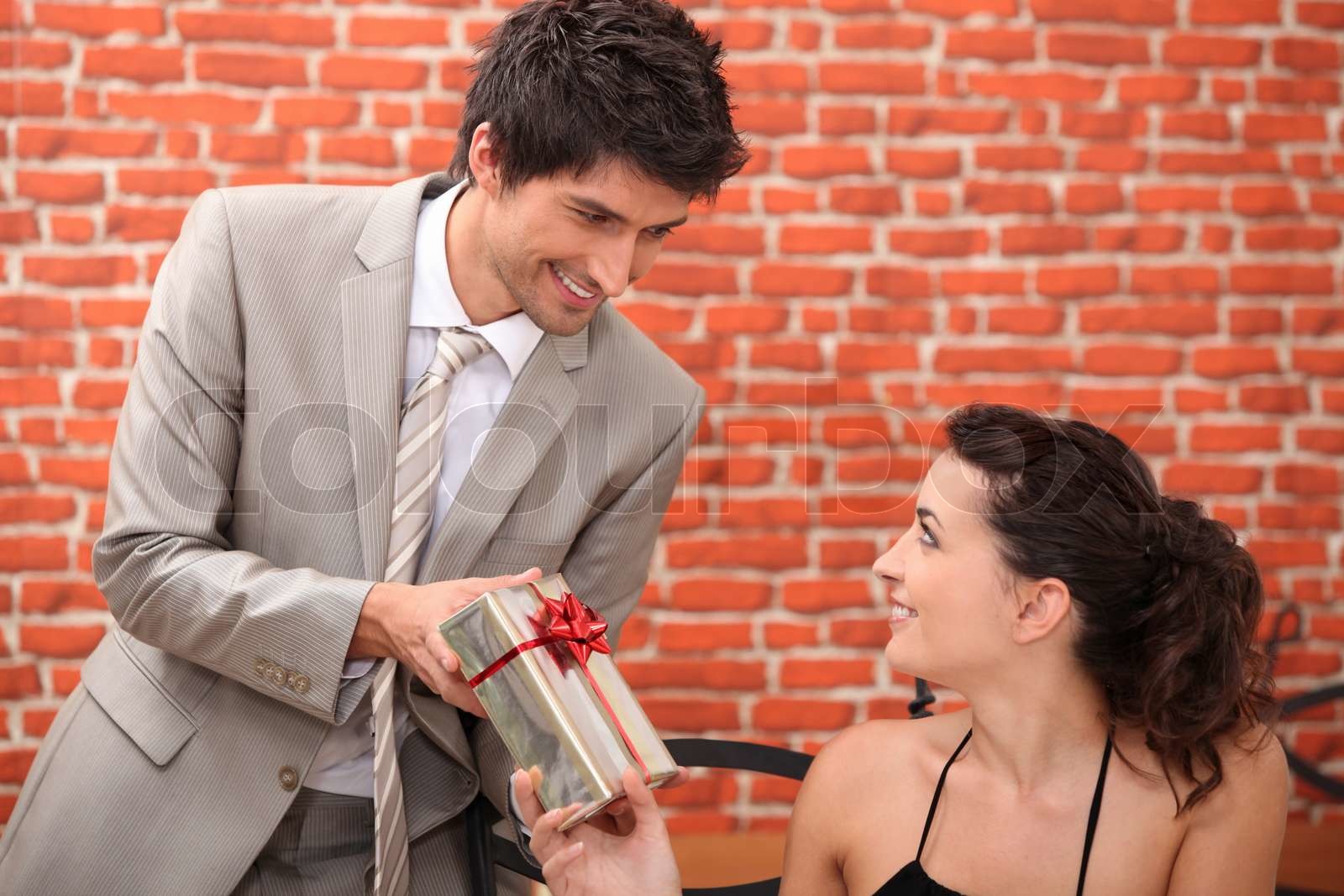 Man offering woman gift in restaurant | Stock image | Colourbox