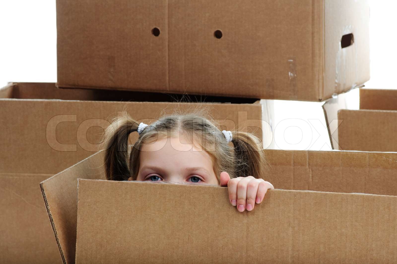 A little girl hiding between boxes | Stock image | Colourbox