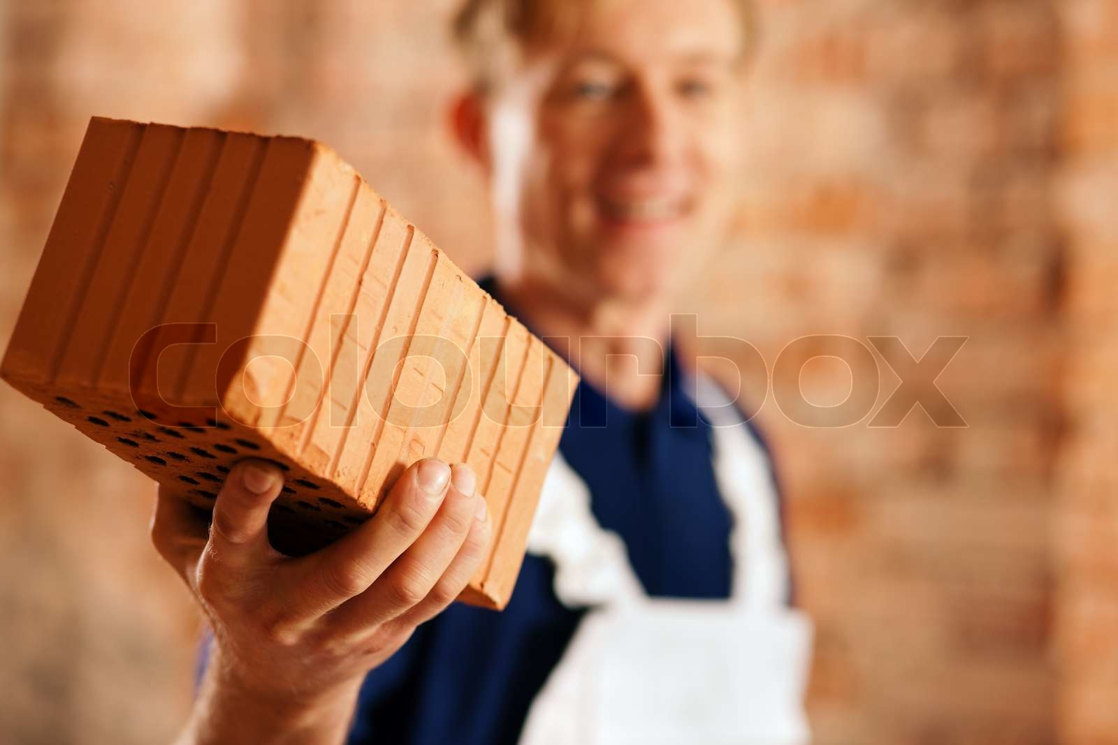 bricklayer with brick on construction site | Stock image | Colourbox