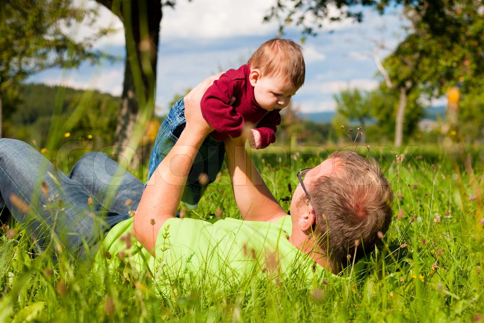 Father playing with baby on meadow | Stock image | Colourbox