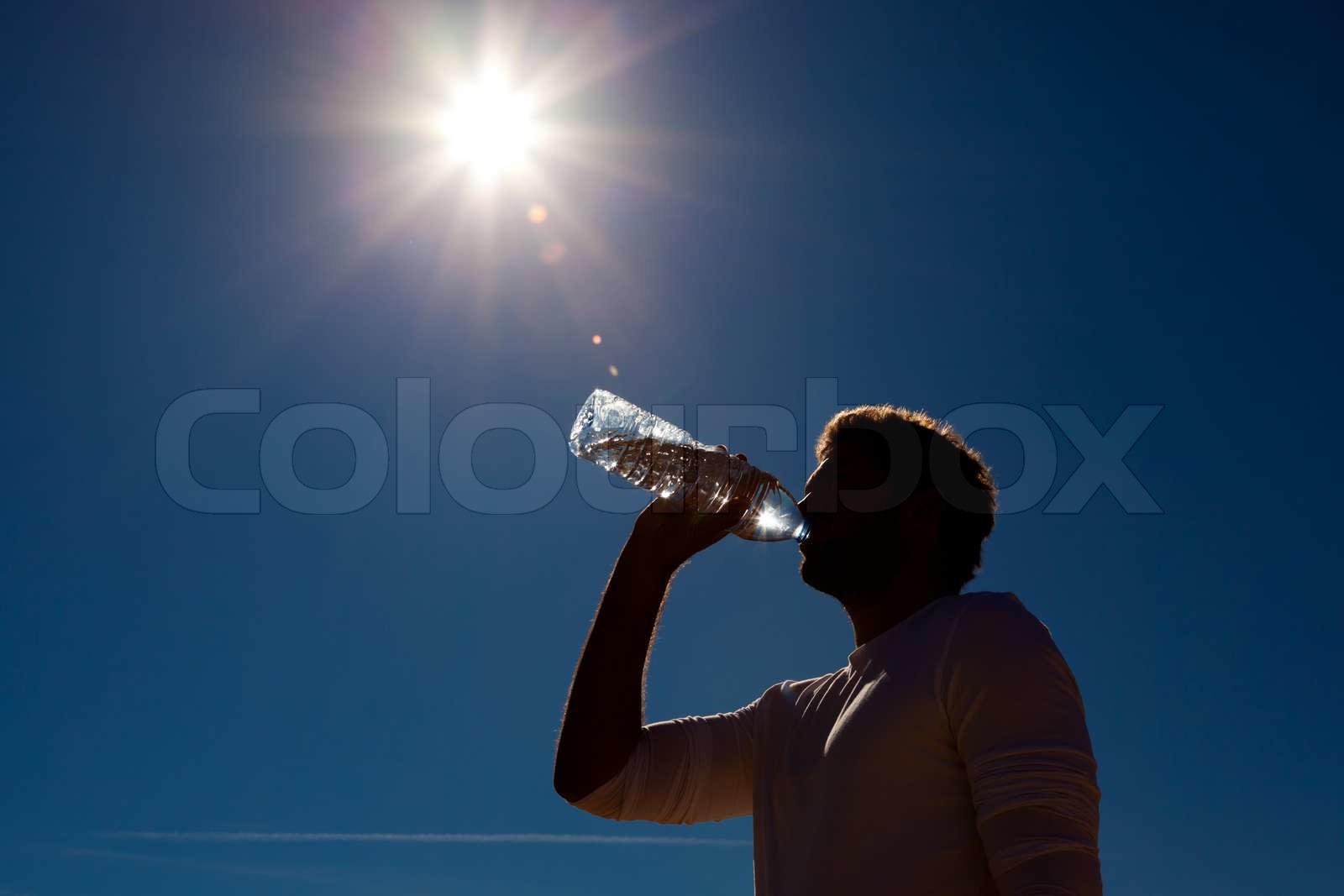 Man drinking bottled water under sun | Stock image | Colourbox