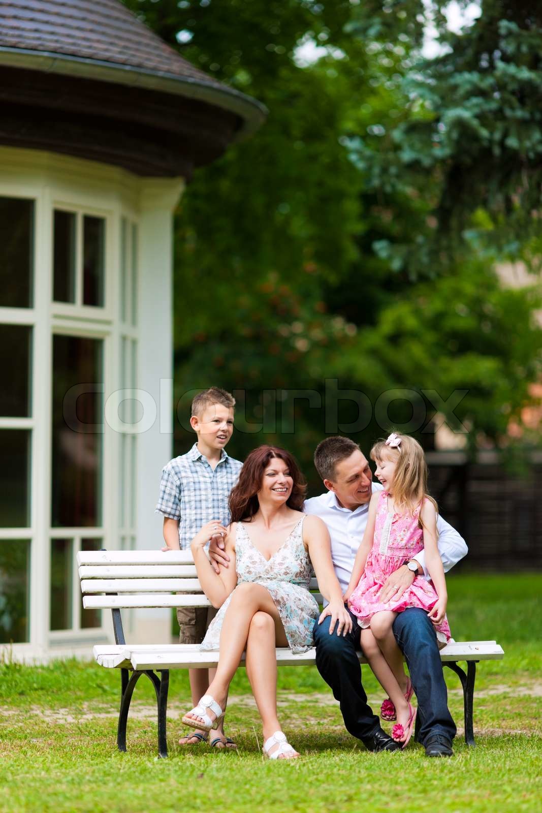 Family sitting in front of their home | Stock image | Colourbox