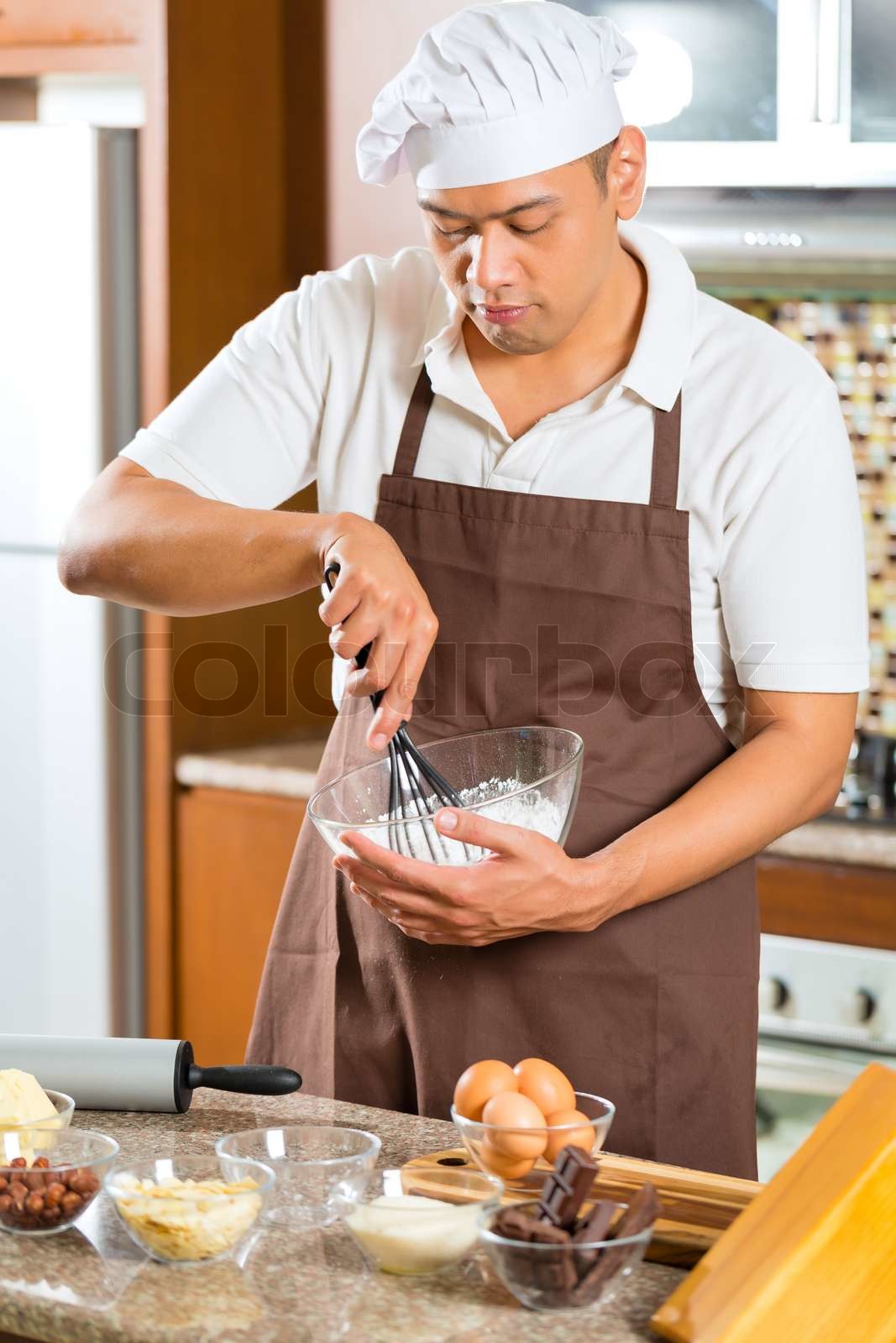 Asian man baking cake in home kitchen | Stock image | Colourbox