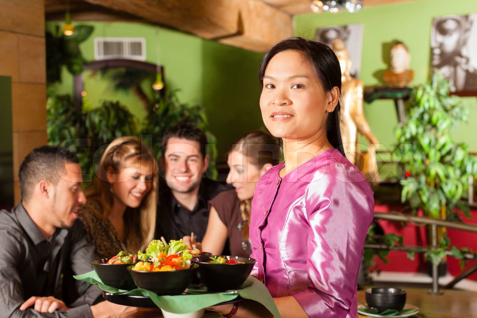 Young people with waitress eating in Thai restaurant | Stock image ...
