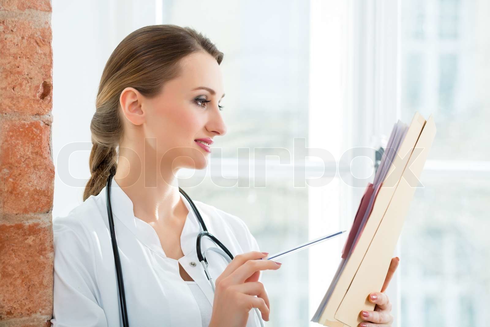 Doctor in clinic reading a file | Stock image | Colourbox