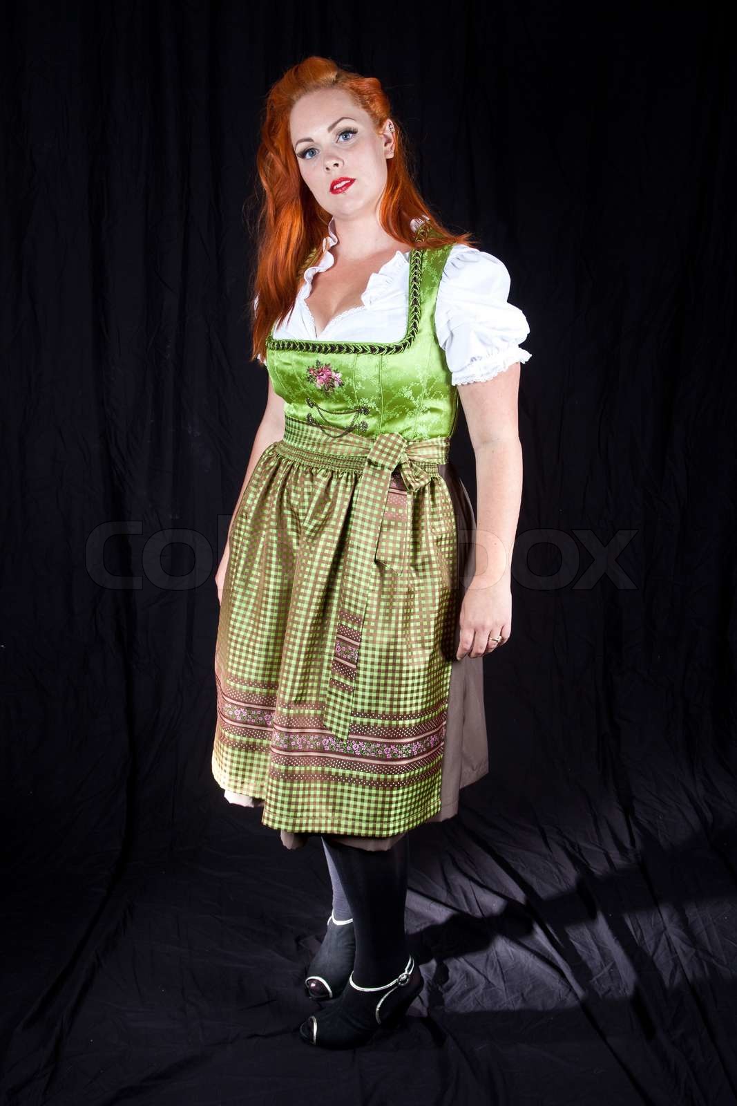 Red hair girl in pin-up style with a bavarian german dress studi ...