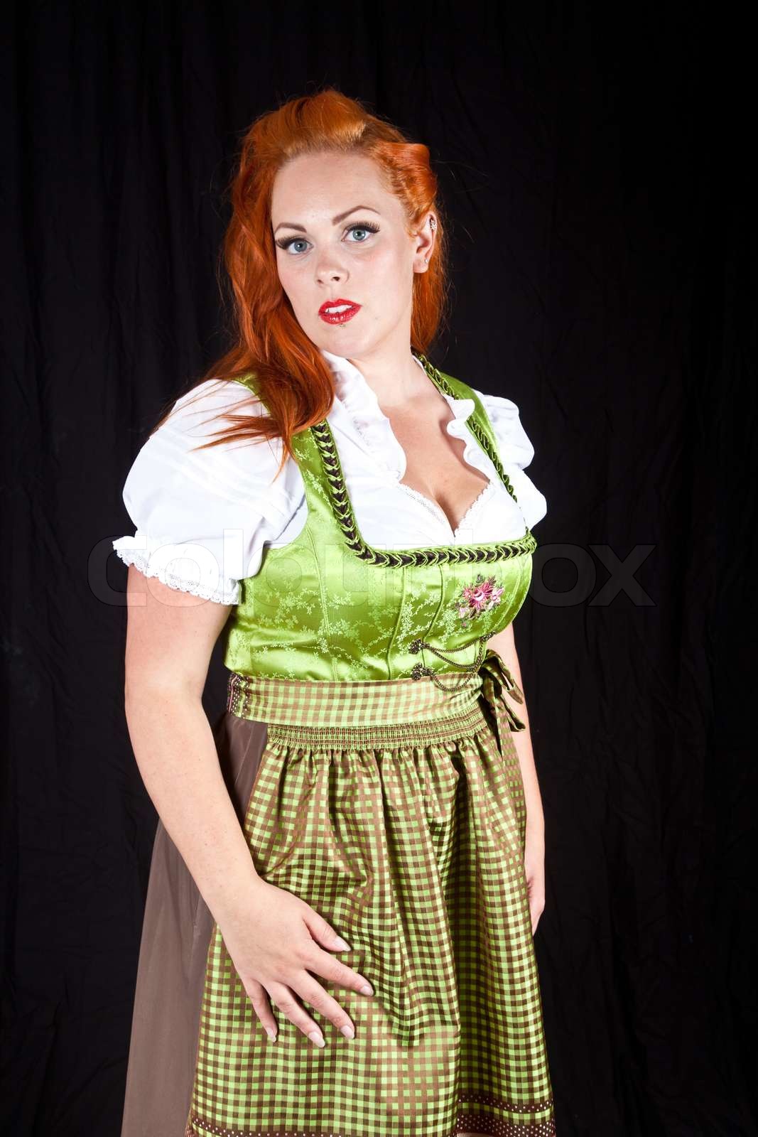 Red hair girl in pin-up style with a bavarian german dress studi ...