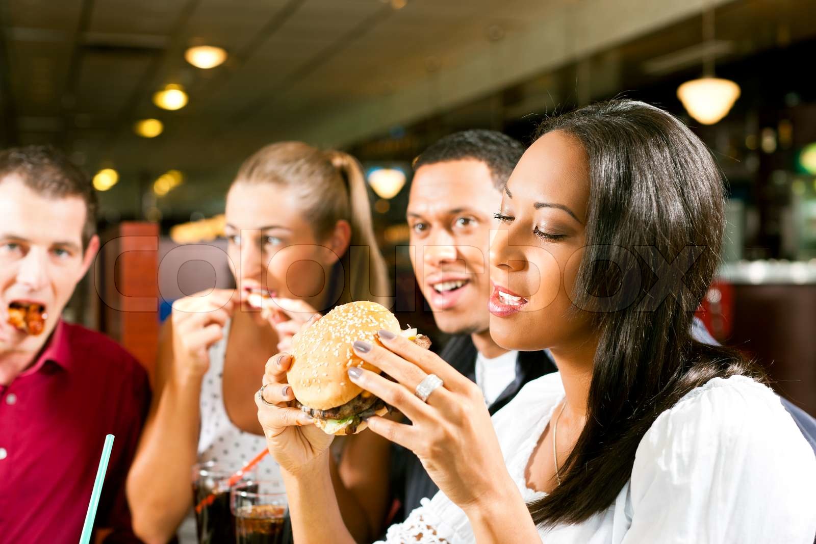 Friends eating fast food in a restaurant | Stock image | Colourbox