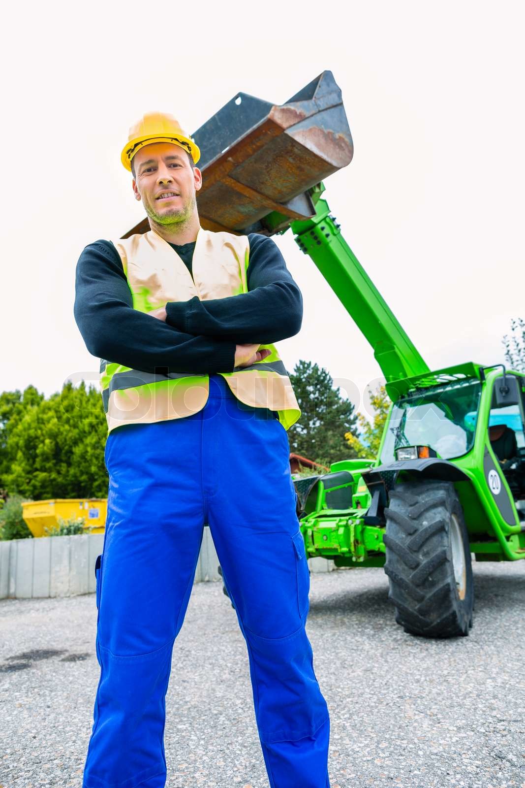Builder in front of construction machinery | Stock image | Colourbox