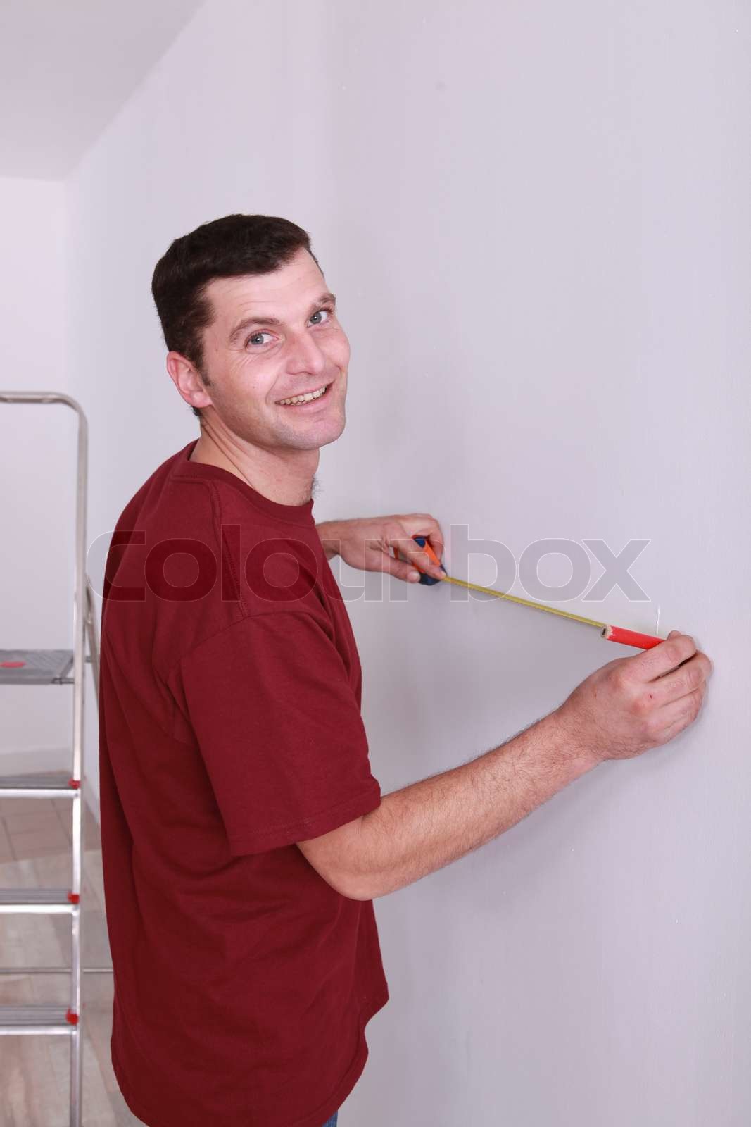 Man measuring wall with tape measure | Stock image | Colourbox