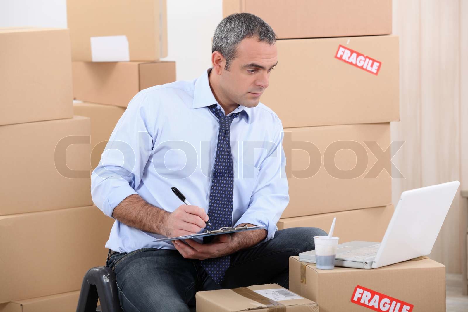 Man surrounded by cardboard boxes using a laptop | Stock image | Colourbox