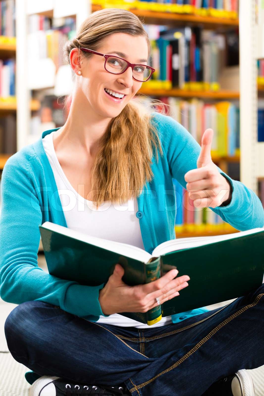 Student with pile of books learning in library | Stock image | Colourbox