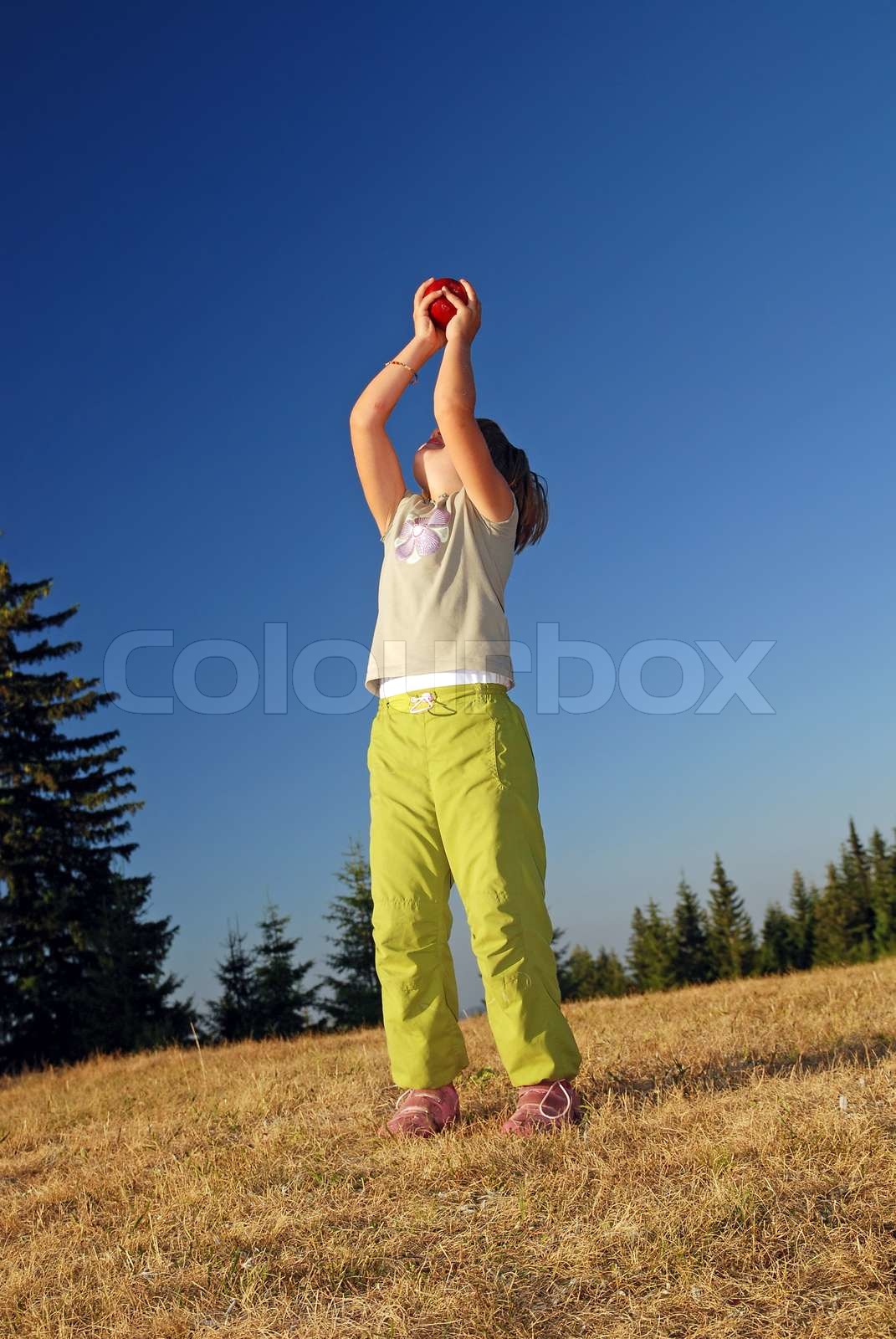 happy girl throwing apple outside | Stock image | Colourbox