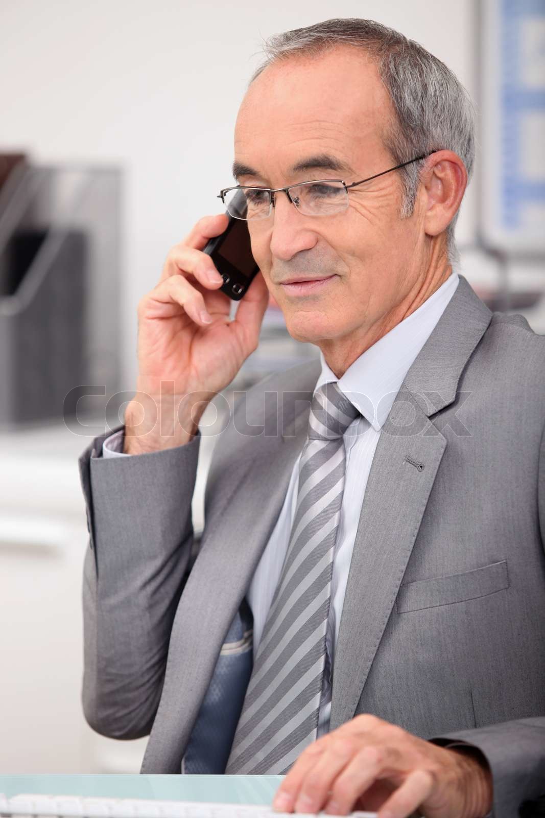65 years old man wearing a grey suit and calling | Stock image | Colourbox