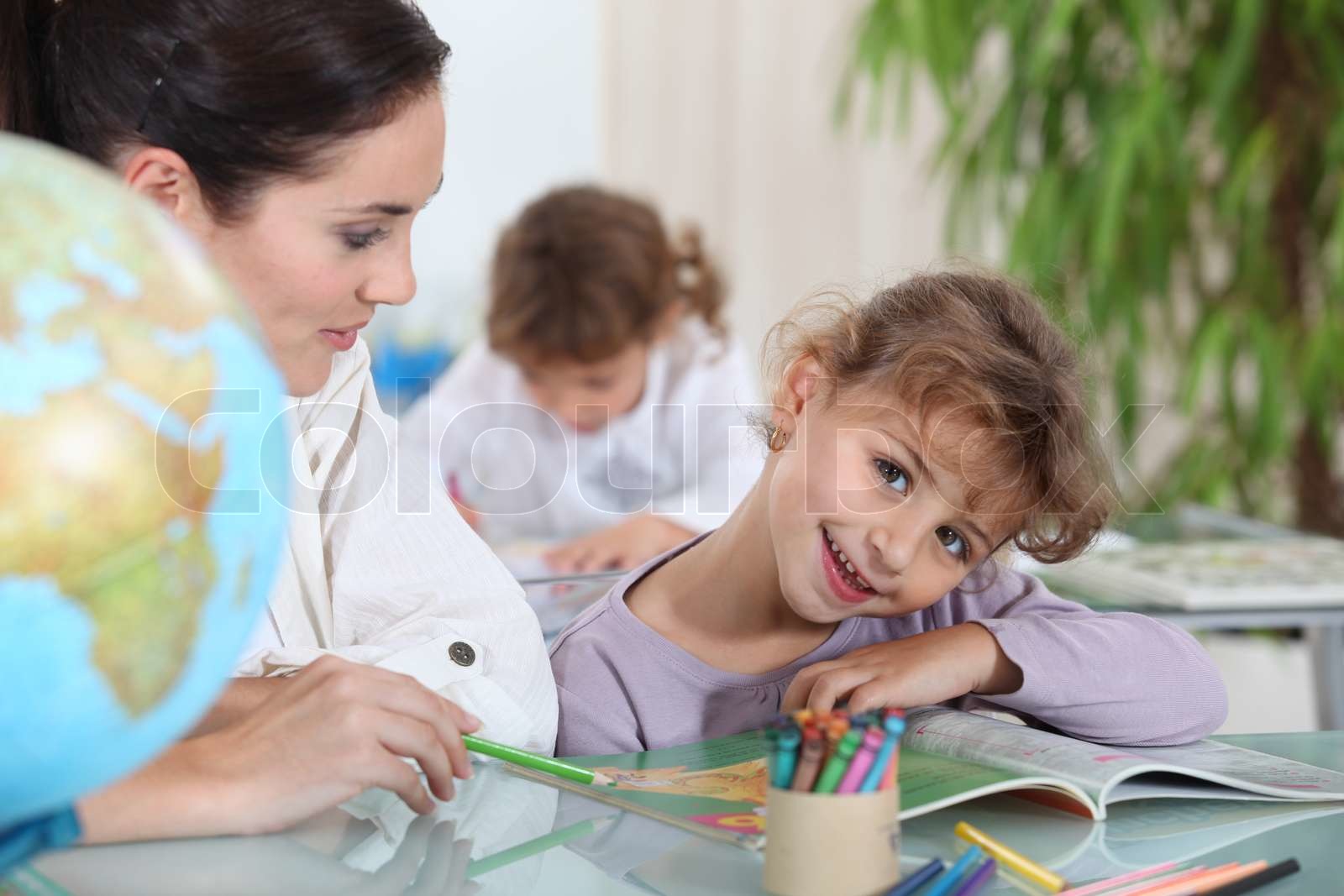 Teacher helping a pupil with her school work | Stock image | Colourbox