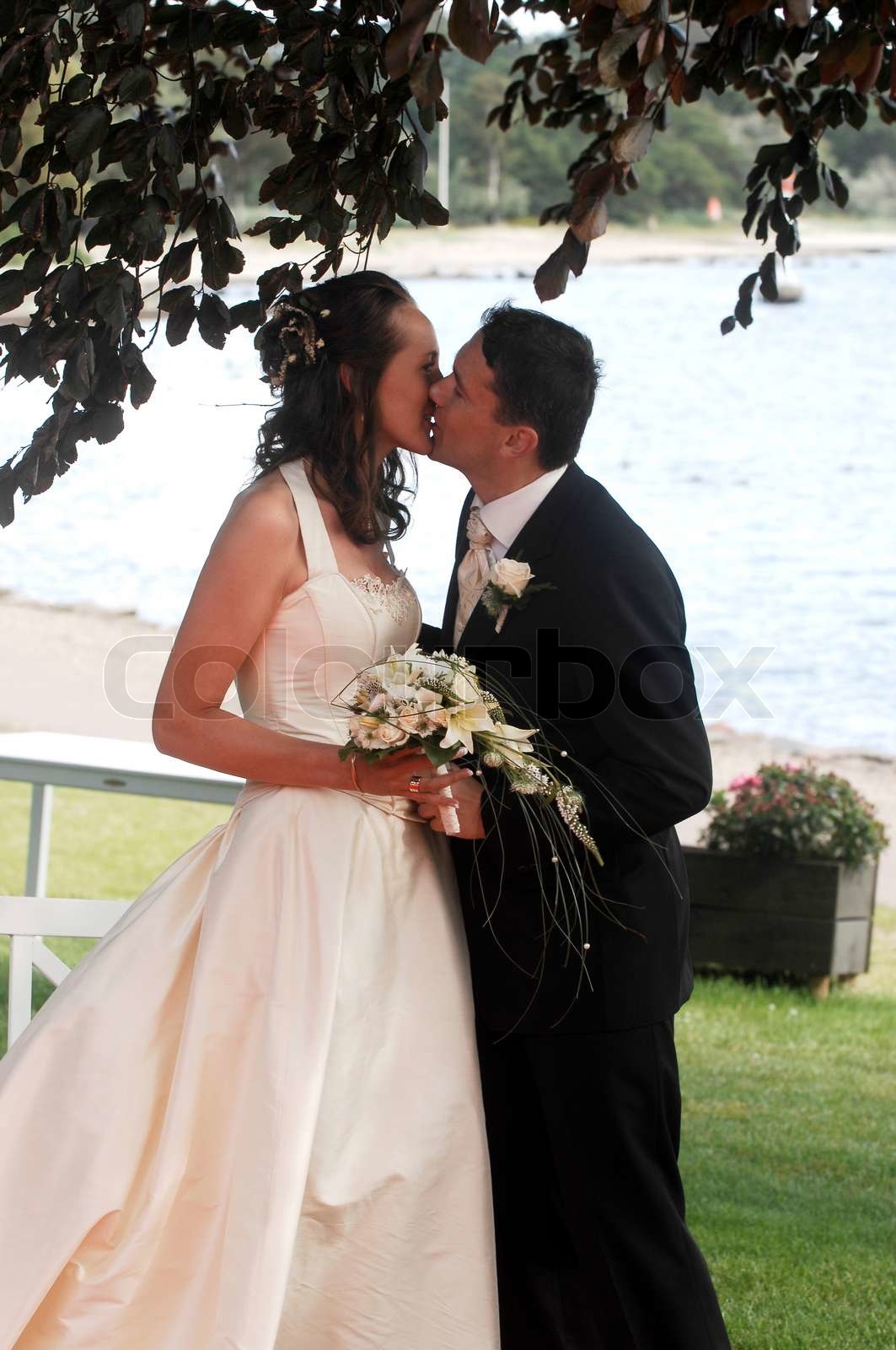 Bridal couple kissing at their outdoor wedding ceremony | Stock image ...