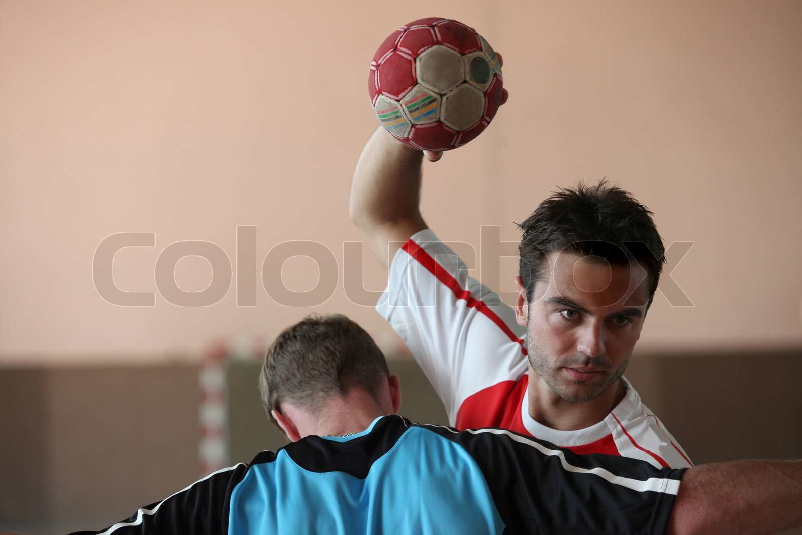 A man playing handball and trying to score in spite of a goalkeeper in ...