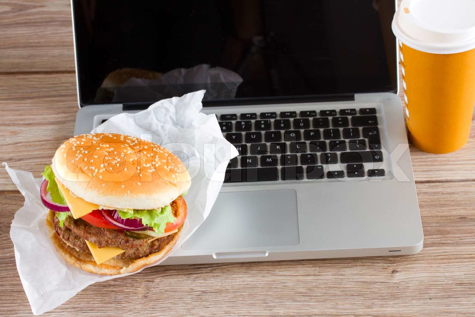 Eating at work place fast food near laptop | Stock image | Colourbox
