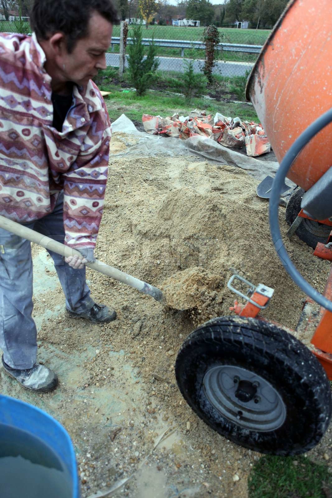 Man shovelling gravel into a mixer | Stock image | Colourbox
