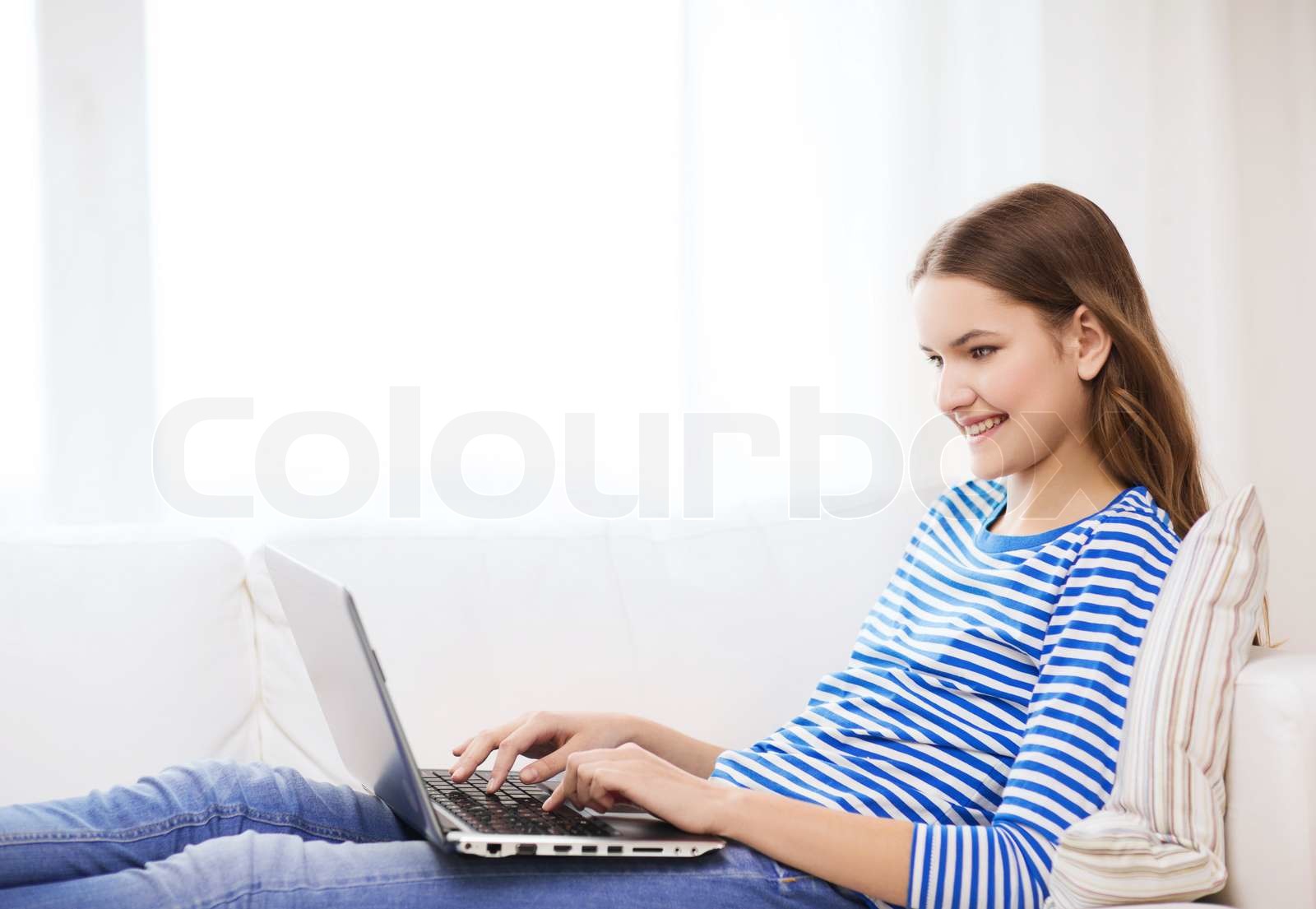 smiling teenage girl with laptop computer at home | Stock image | Colourbox