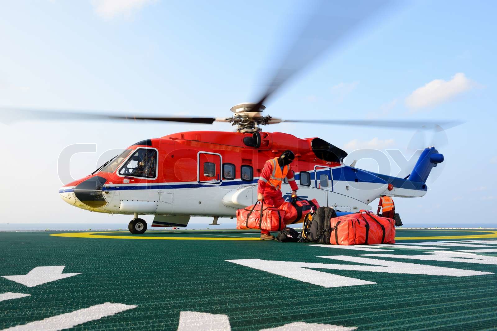 The helicopter landing officer loading baggage to helicopter at oil rig ...