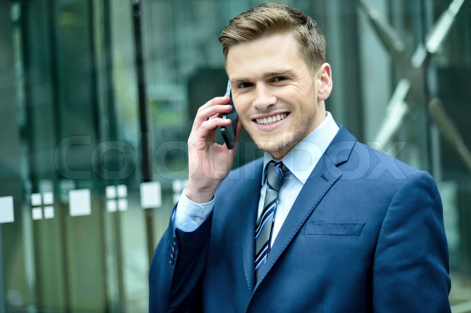 Smiling man in suit talking on cellphone | Stock image | Colourbox