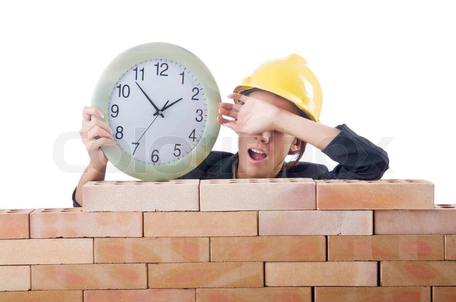 Woman construction worker with clock on white | Stock image | Colourbox